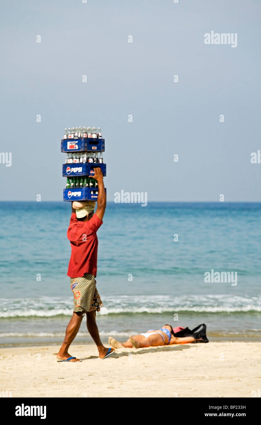 Porter carrying Pepsi crates on Kovalam Beach in Kerala while tourist ...