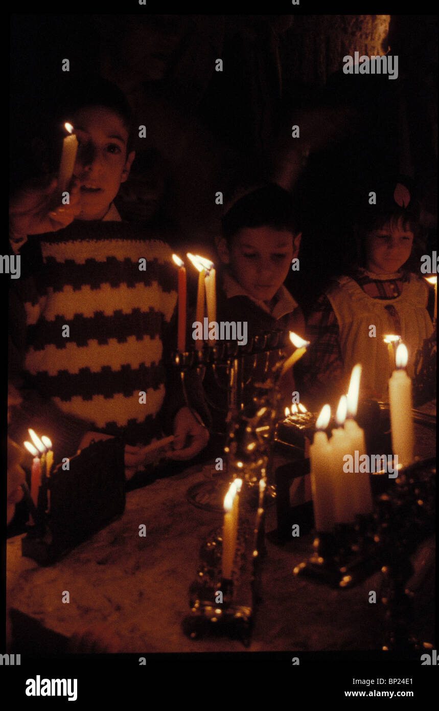 A FAMILY IN JERUSALEM LIGHTING THE THIRD CANDLE. IN SOME FAMILIES IT IS ...