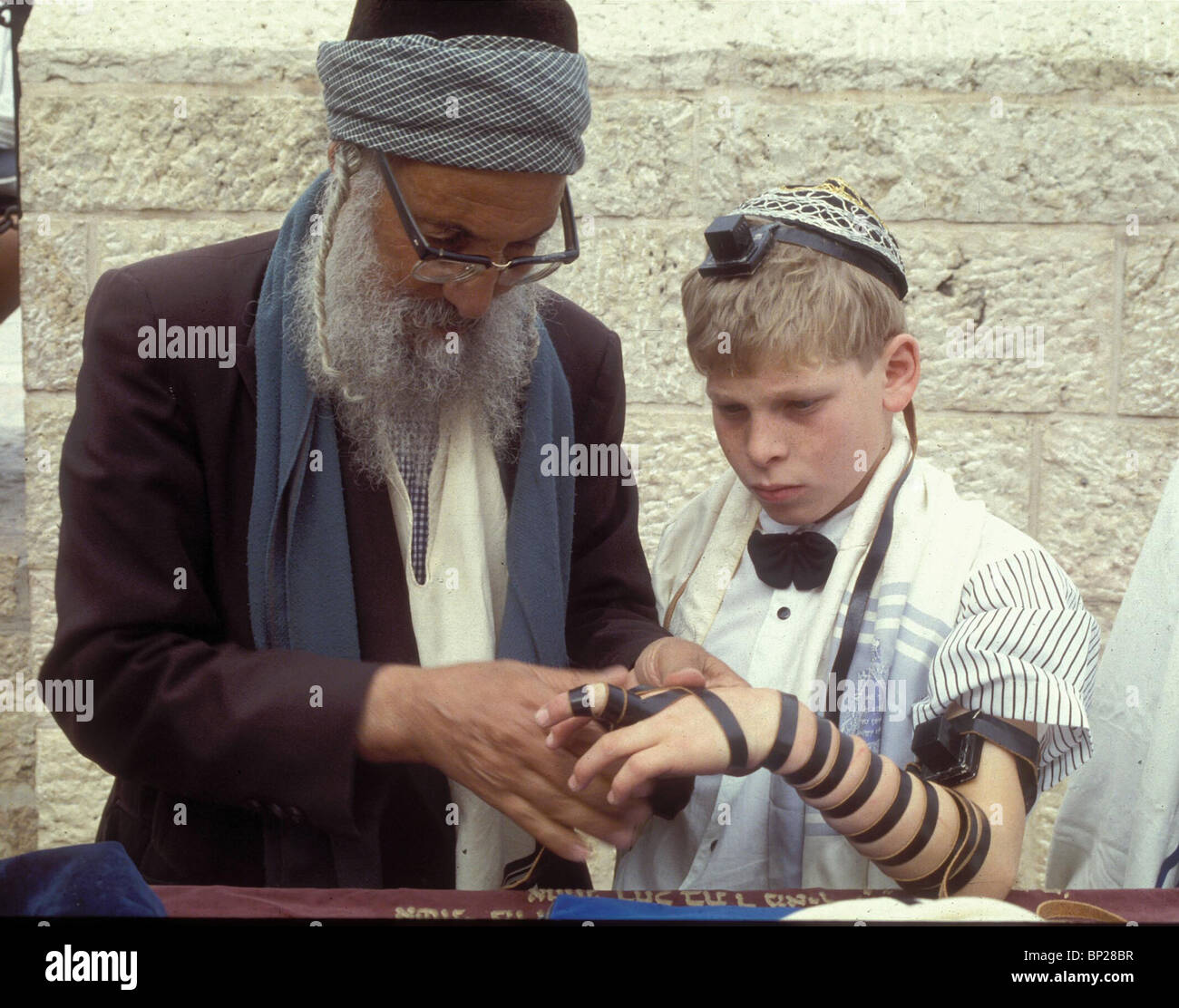 2082. A BOY IS PUTING ON PHYLACTERY IN PREPARATION FOR HIS 'BARMITZVAH ...