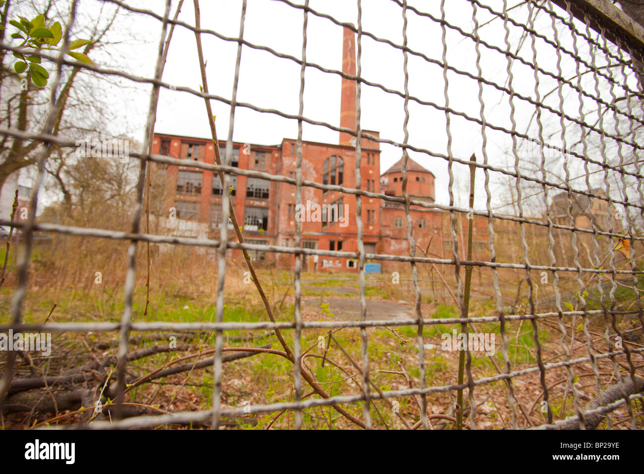 Abandoned old factory made out of red brick, seen through a fence Stock ...