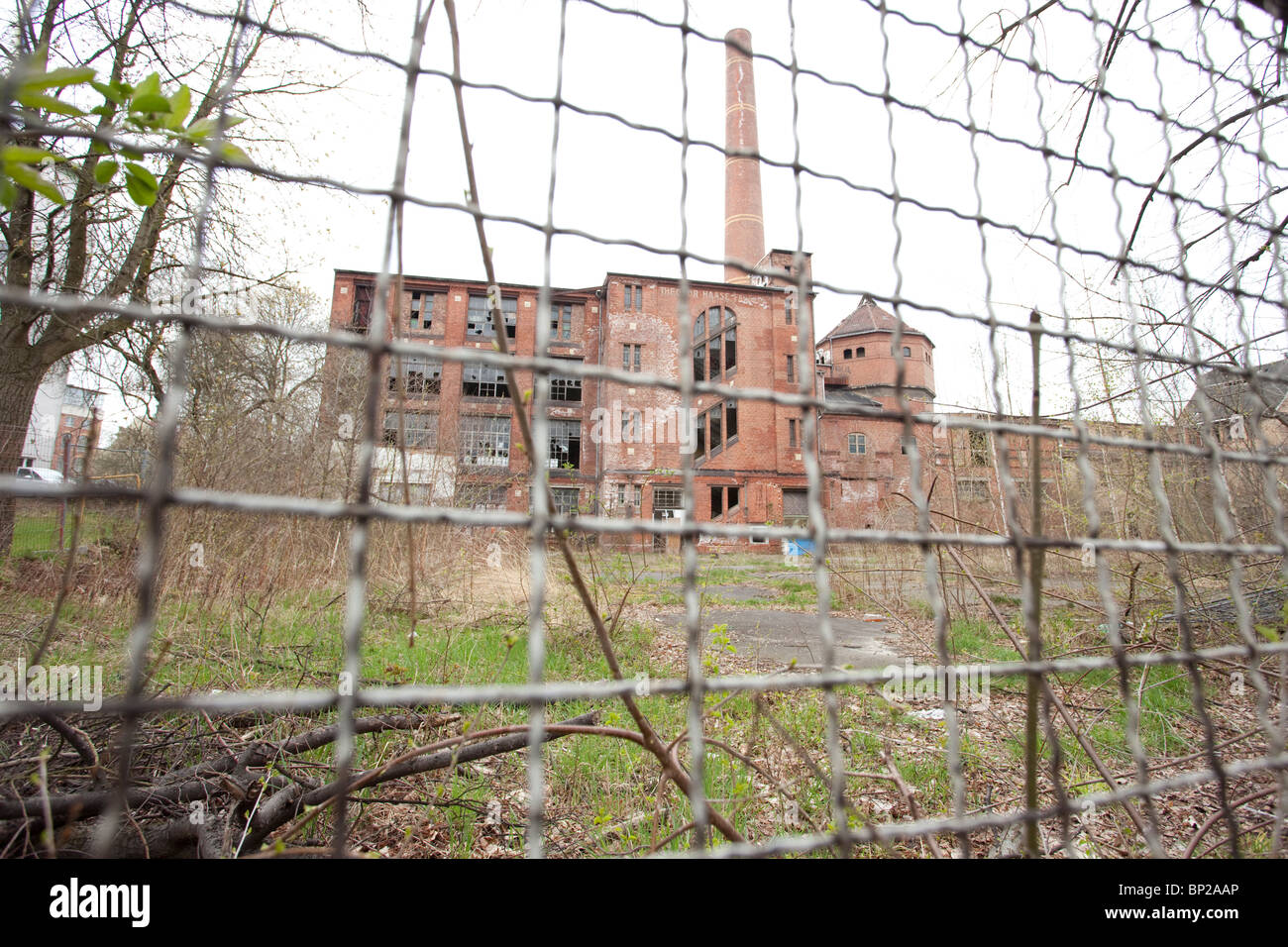 Abandoned old factory made out of red brick, seen through a fence Stock ...