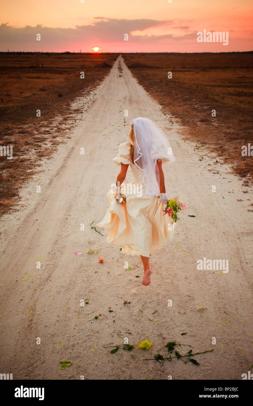 Runaway bride down dirt road Stock Photo - Alamy