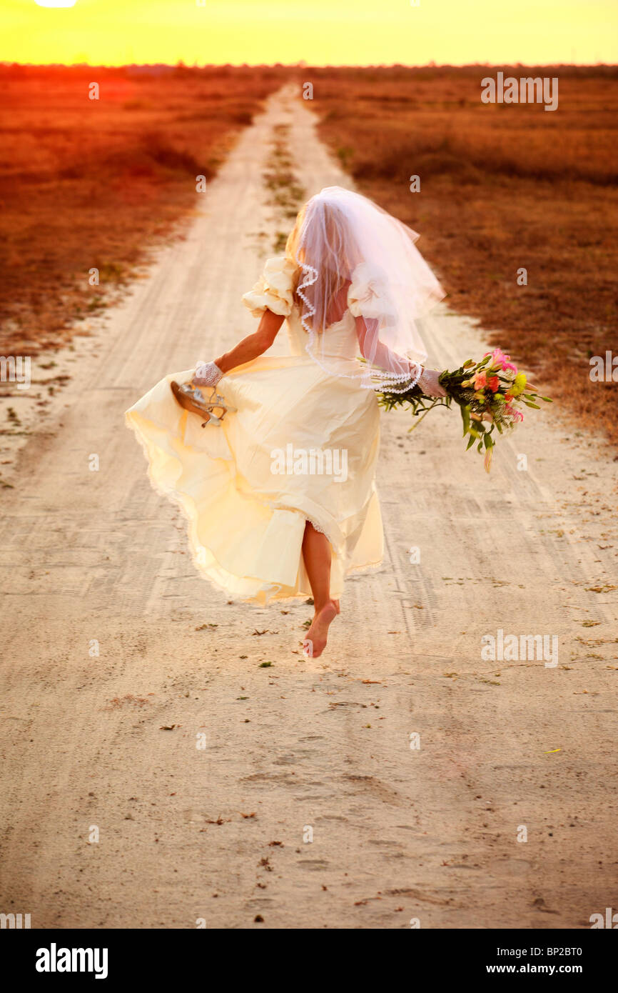 Runaway bride down dirt road Stock Photo - Alamy
