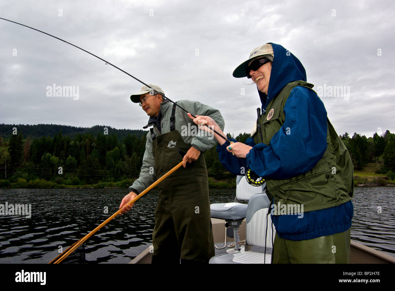 Female sport angler playing rainbow trout to fishing guide guide ...