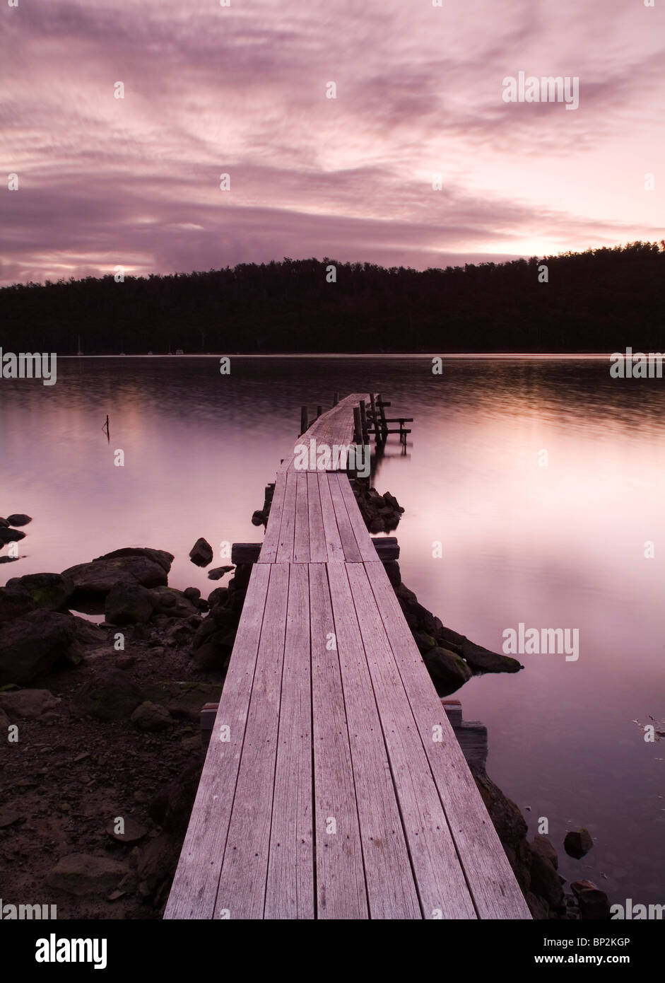 Purple and pink sunset over water and jetty Stock Photo - Alamy