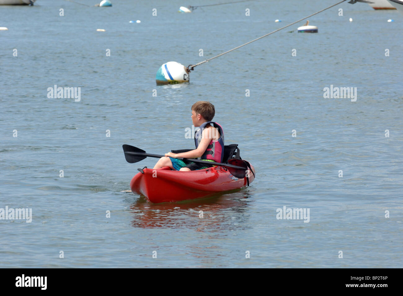 Young white boy paddling on a red kayak Stock Photo - Alamy
