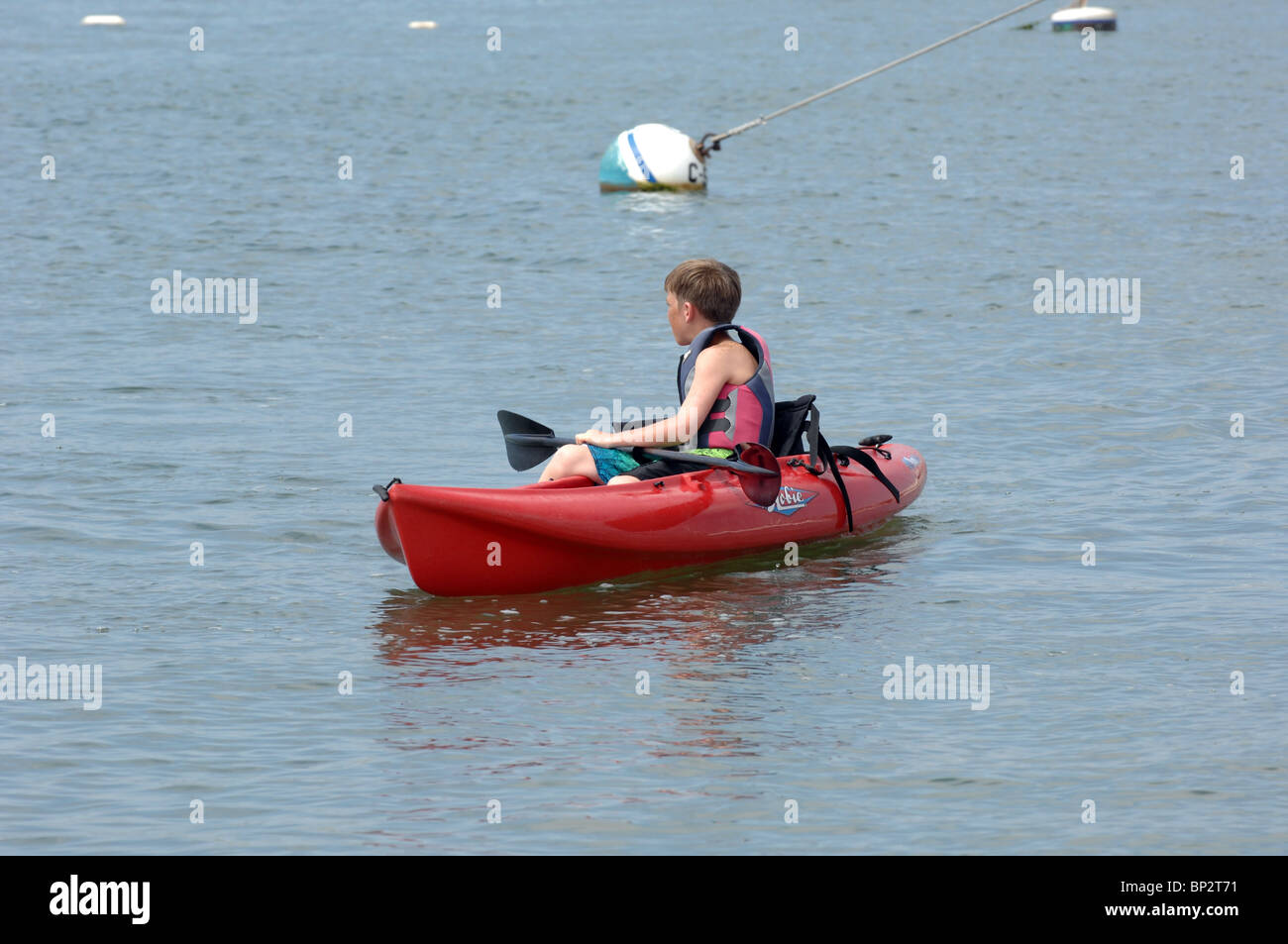 Young white boy paddling on a red kayak Stock Photo - Alamy