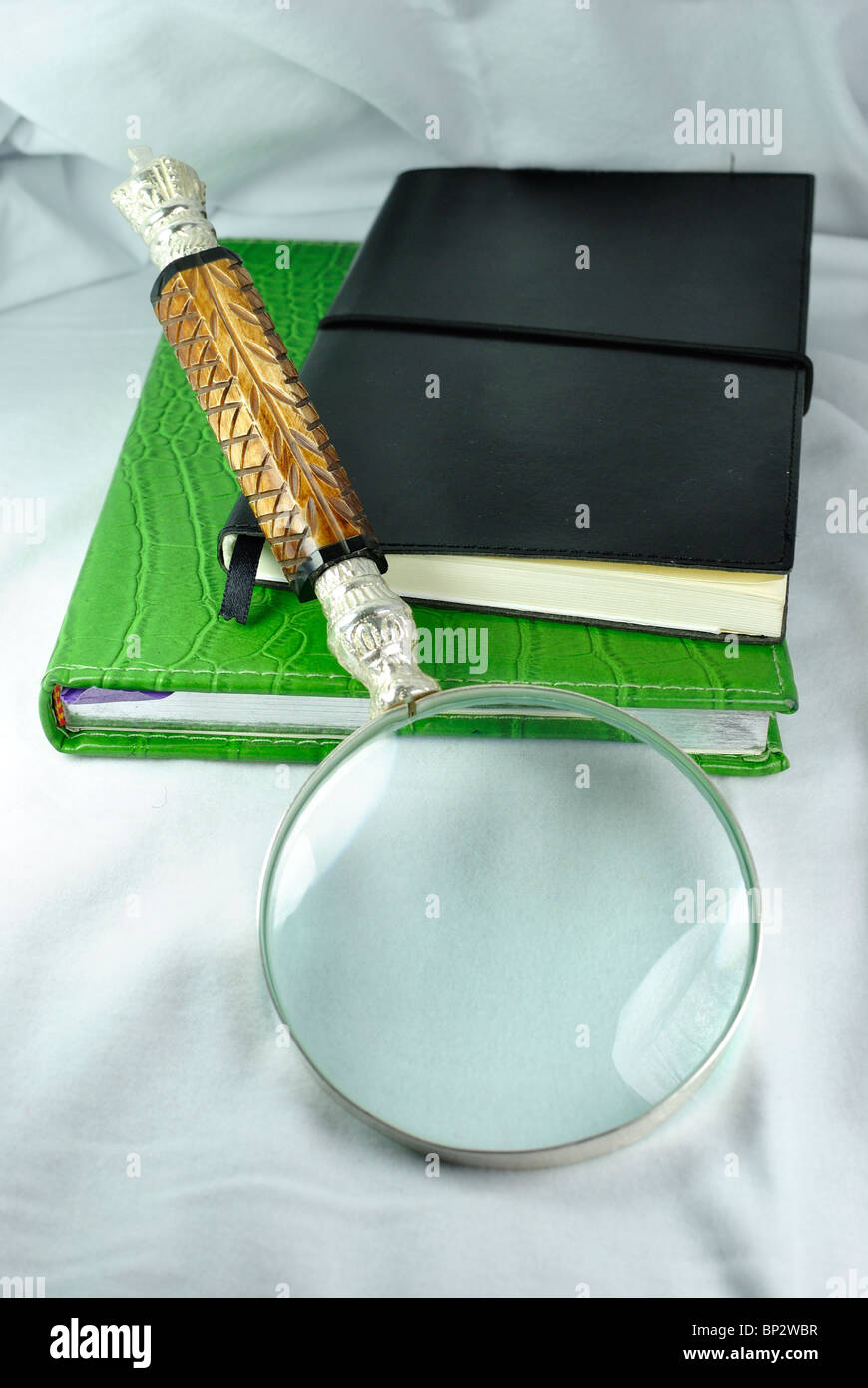 Magnifying glass on top of notebooks Stock Photo - Alamy