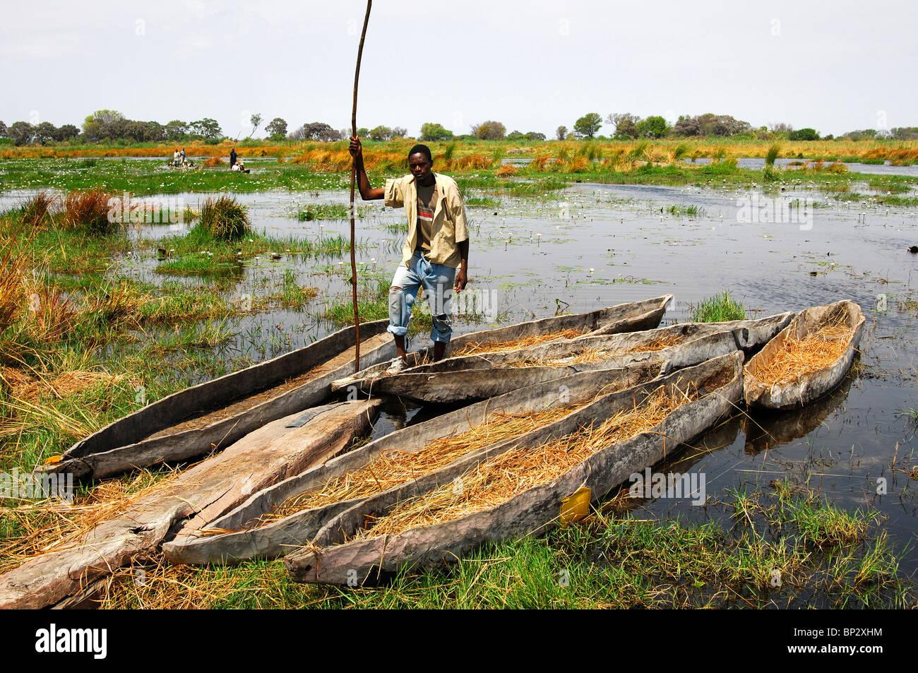 Young man of the local Bayei community standing with a pole in a ...