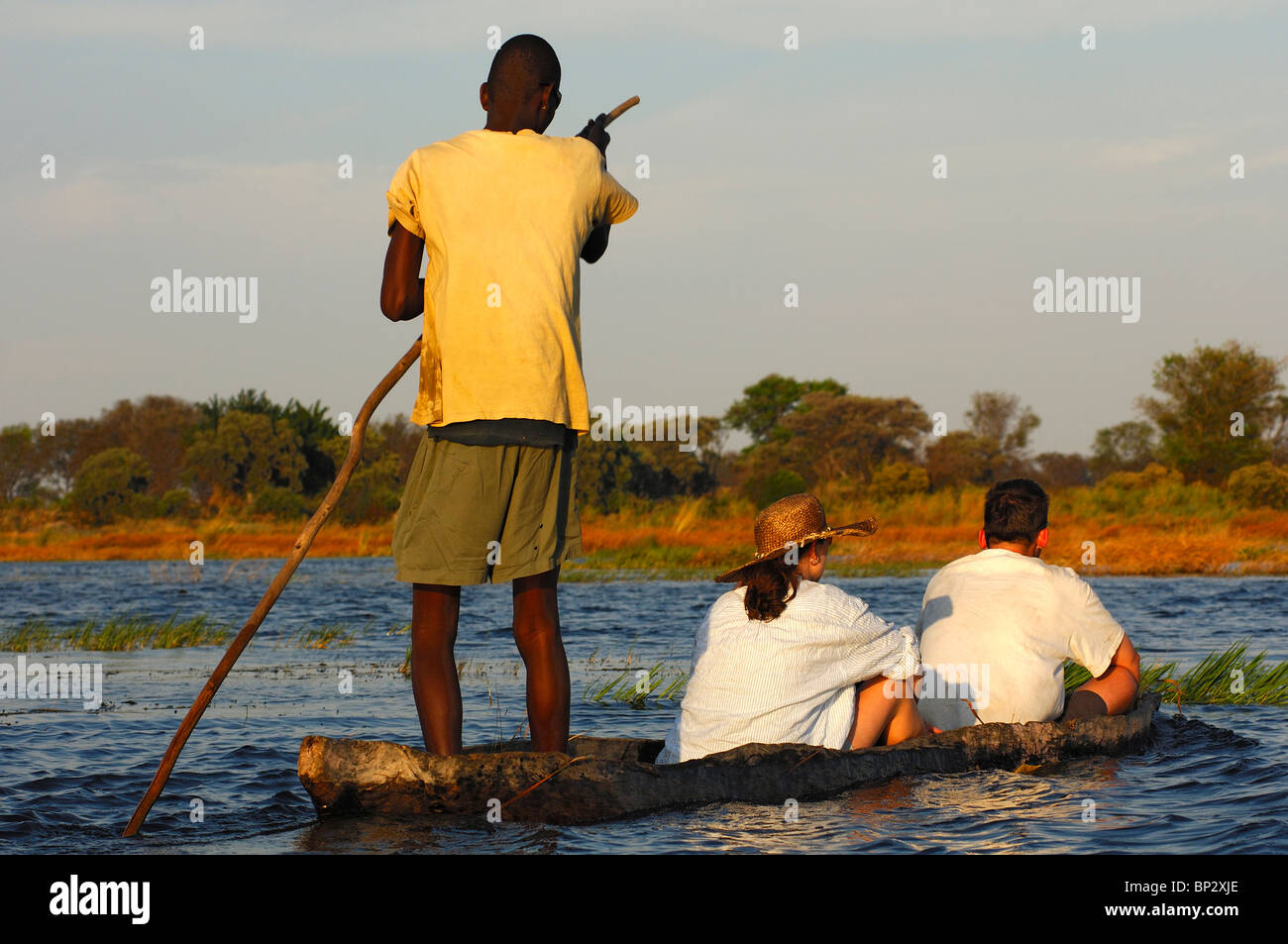 Poler with tourists in a traditional mokoro logboat on excursion in the ...