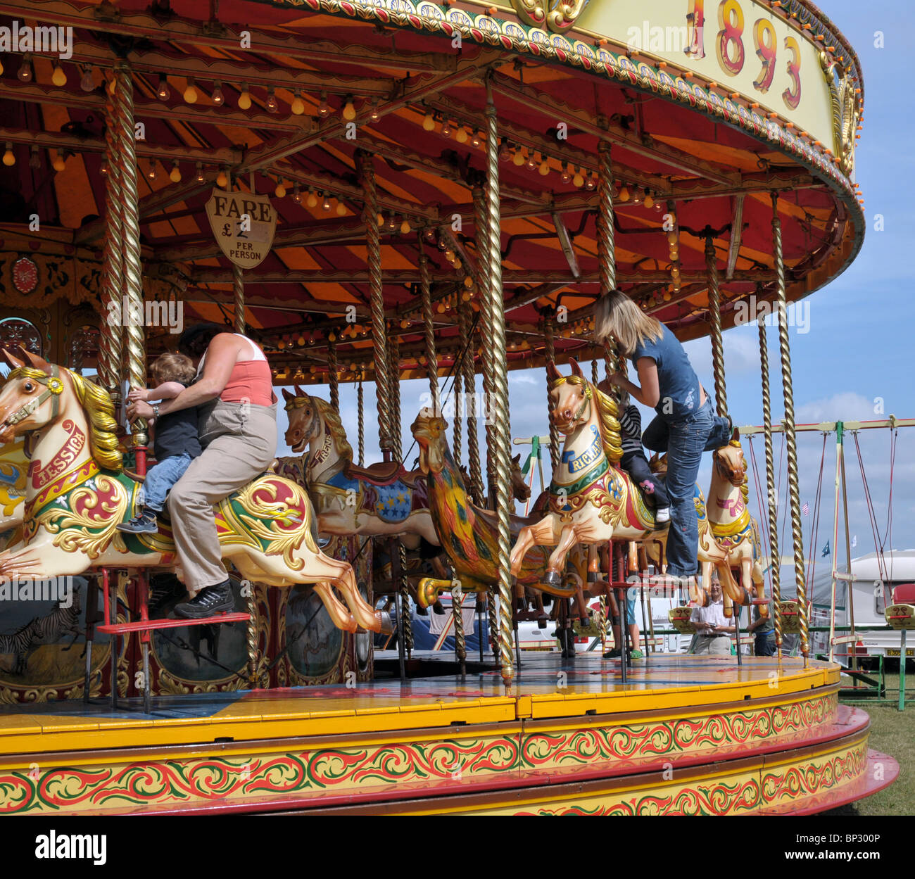 mothers and children getting ready to have a ride on the carousel at ...