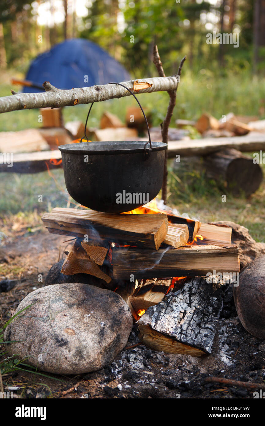 Preparing food on campfire in wild camping Stock Photo - Alamy