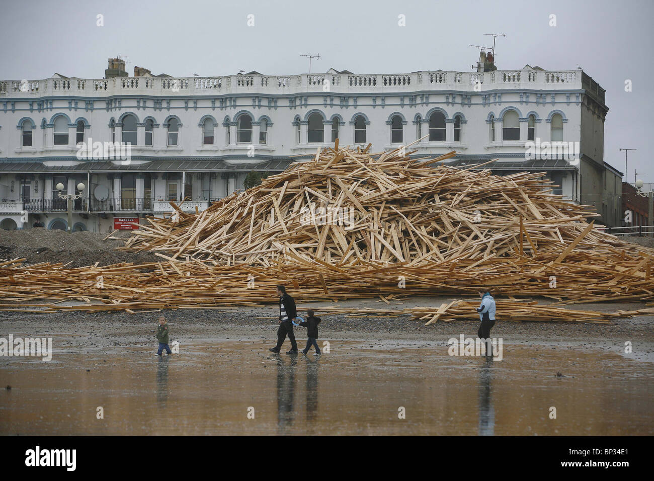A family walk past piles of timber washed up on Worthing beach. Picture ...
