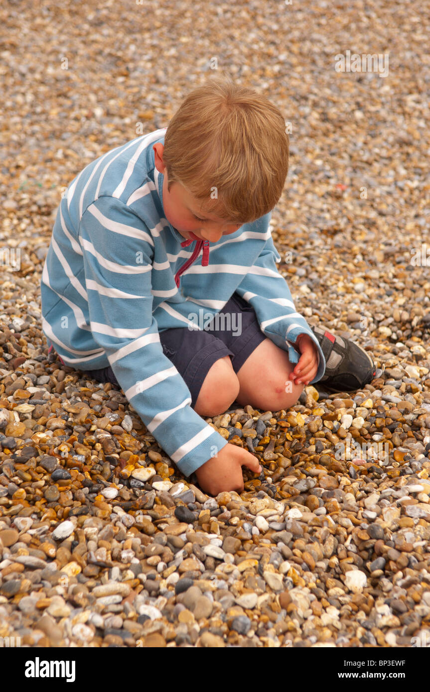 A MODEL RELEASED picture of a 6 year old boy picking up stones near the ...