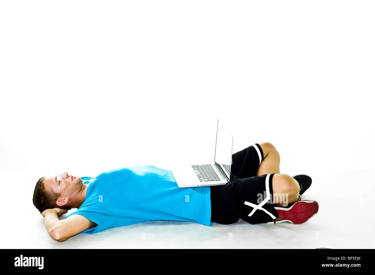 Young man resting with his computer lying on him, isolated on white ...
