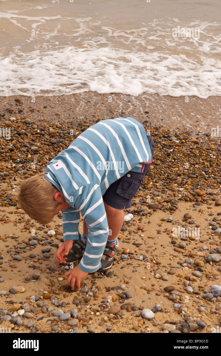A MODEL RELEASED picture of a 6 year old boy picking up stones near the ...