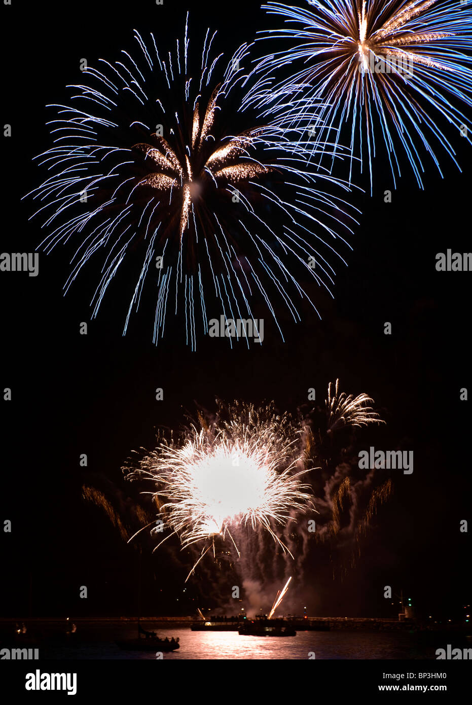 multi coloured fireworks erupting in the night sky over water Stock ...