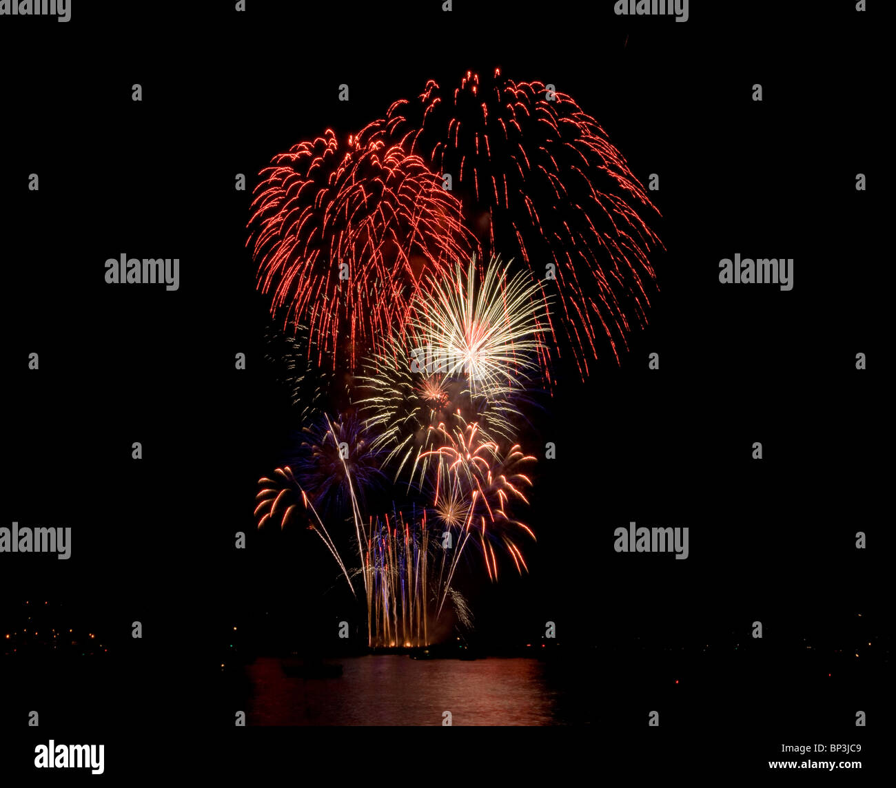 multi coloured fireworks erupting in the night sky over water Stock ...