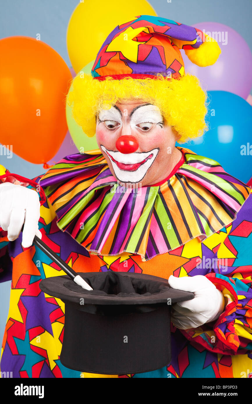 Birthday clown performing a magic act with a tophat and wand Stock ...