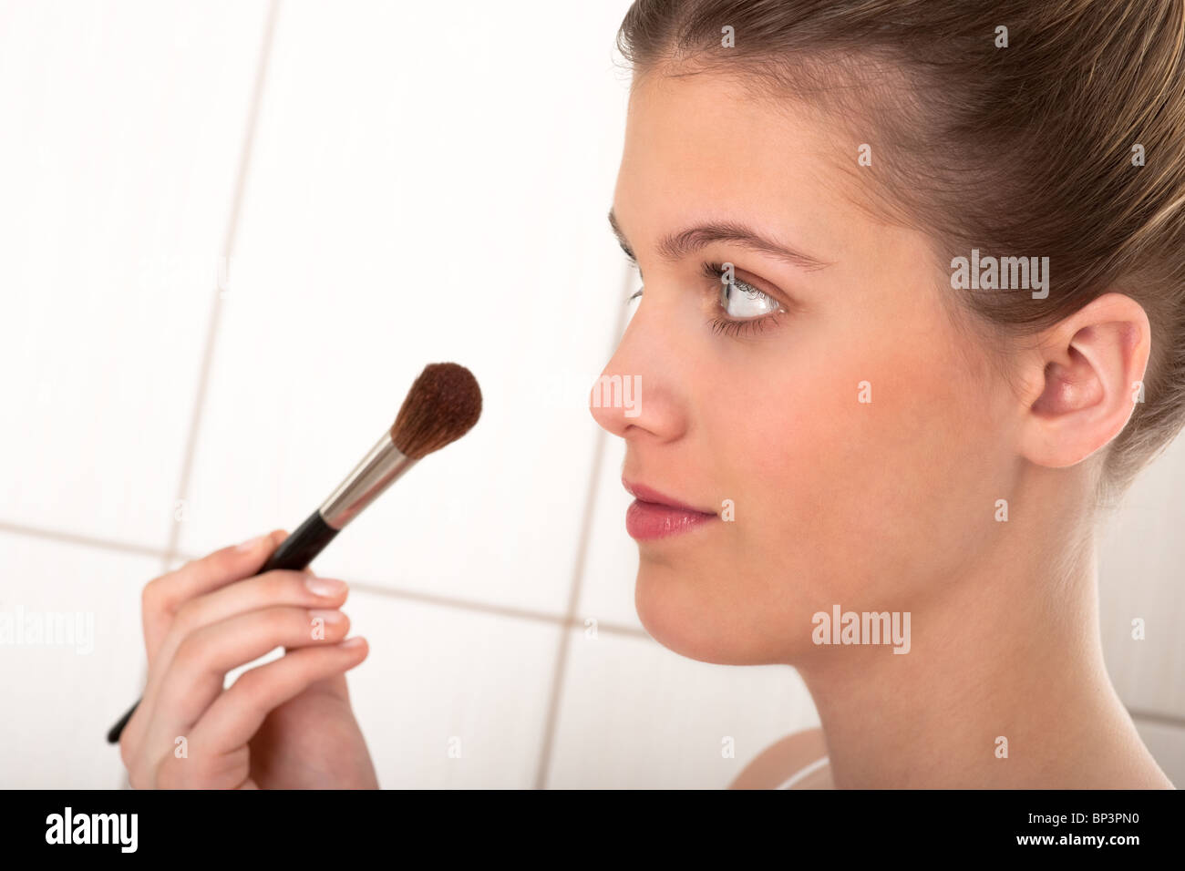 Young woman applying powder in the bathroom Stock Photo - Alamy