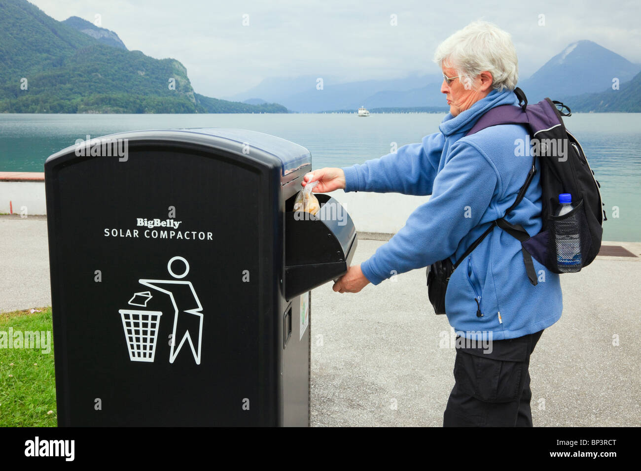 Woman throwing rubbish into a BigBelly Solar powered litter compactor ...