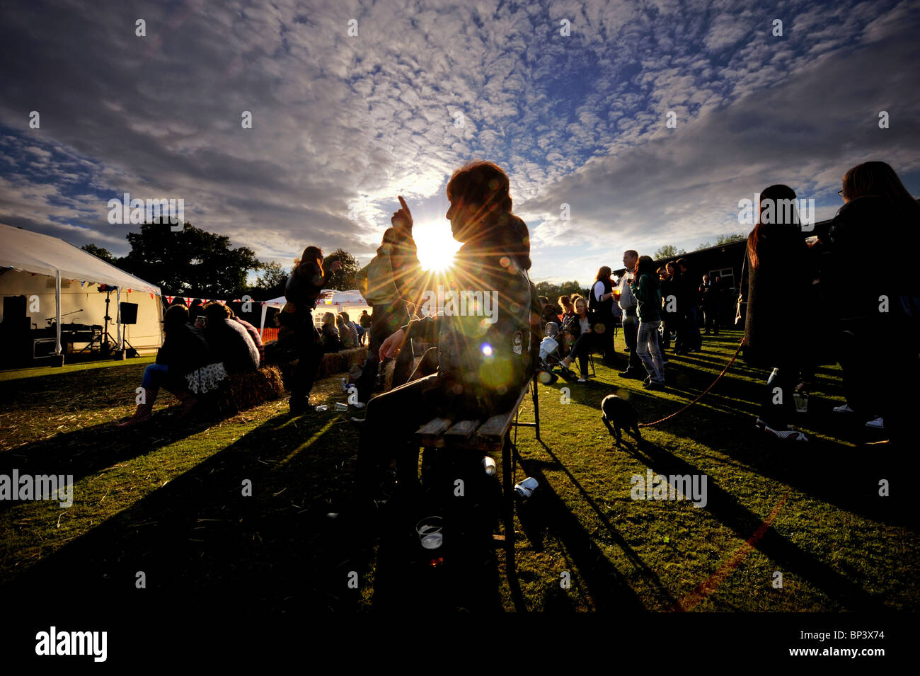 A festival goer silhouetted against the sun at a summer music festival ...