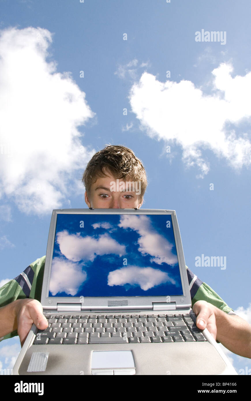 teenager holding laptop with cloud images representing cloud computing ...