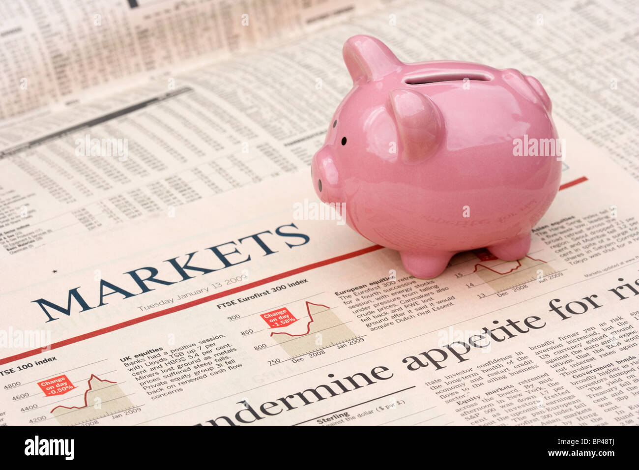 pink piggy bank sitting on a copy of the financial times newspaper ...