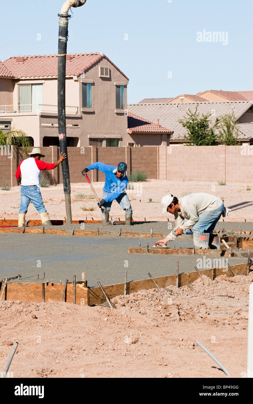 A crew of construction workers pour a concrete pad for a new house ...