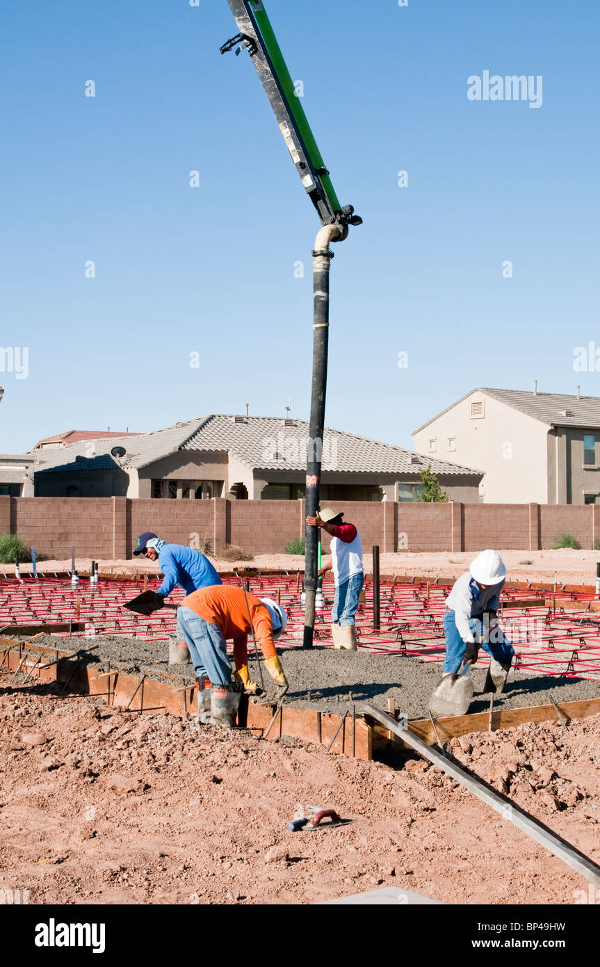 A crew of construction workers pour a concrete pad for a new house ...
