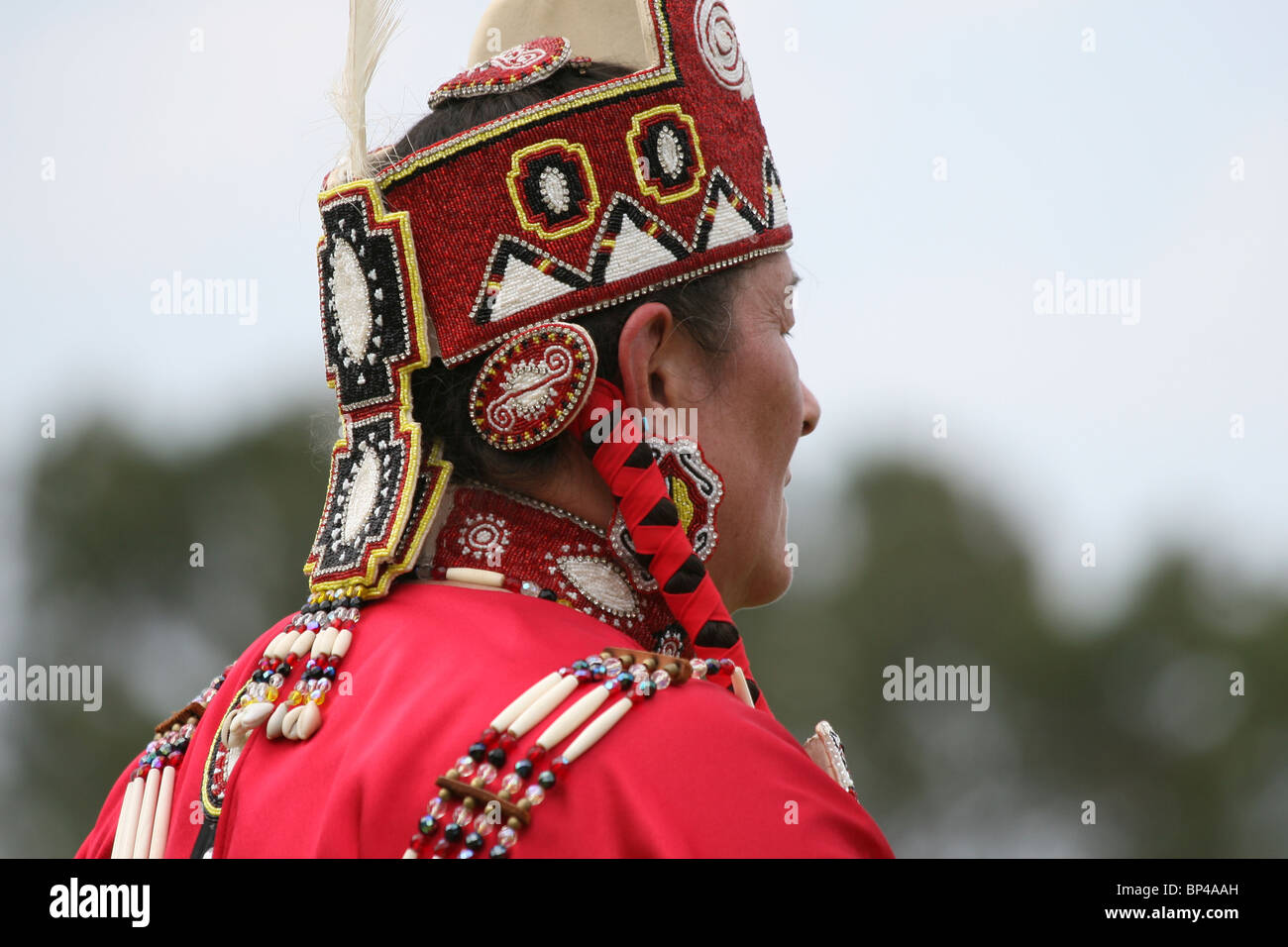 A Native American woman in full traditional regalia parades in the ...