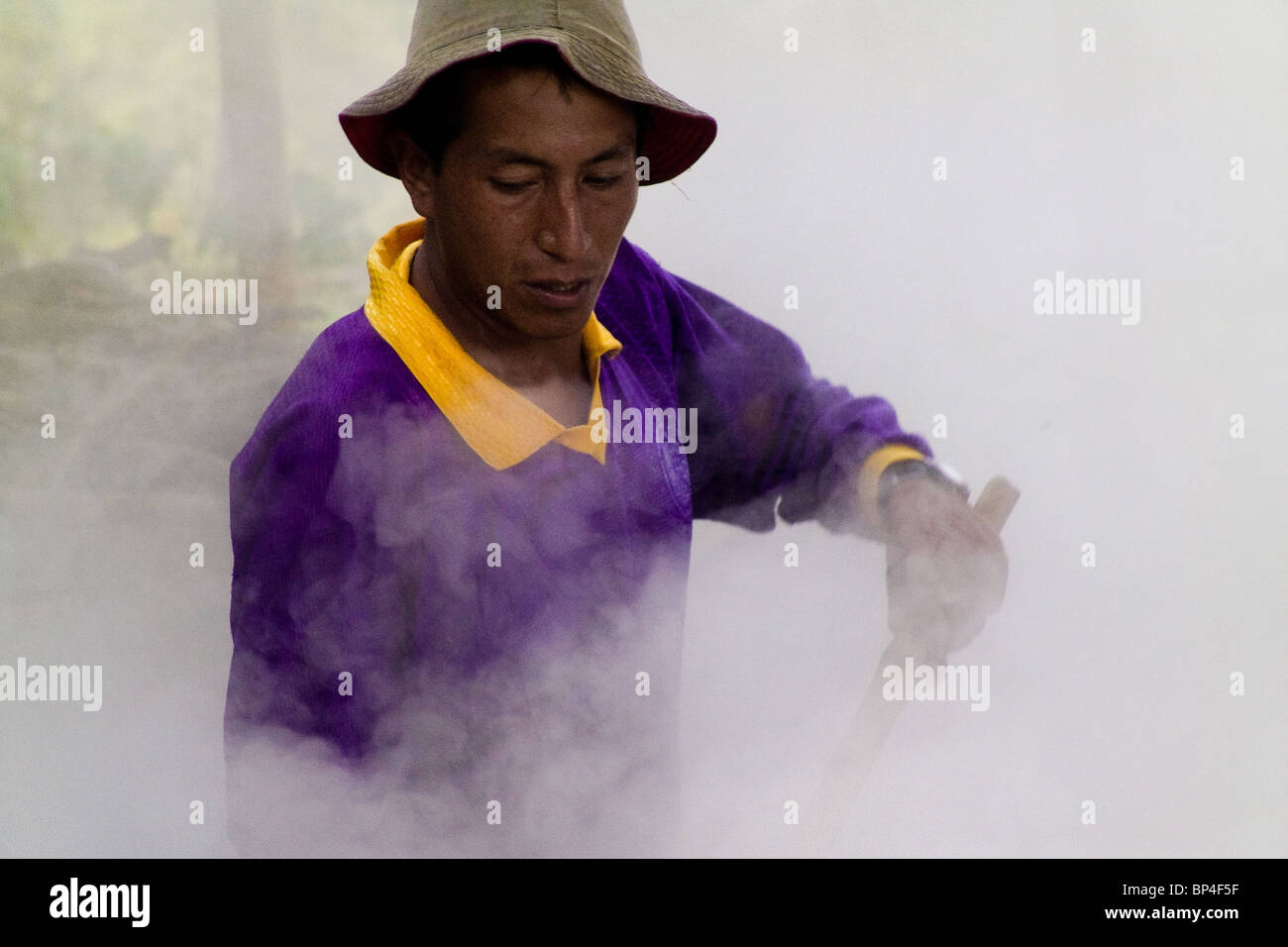A Colombian man works in the smoke of boiling sugarcane juice in a farm ...