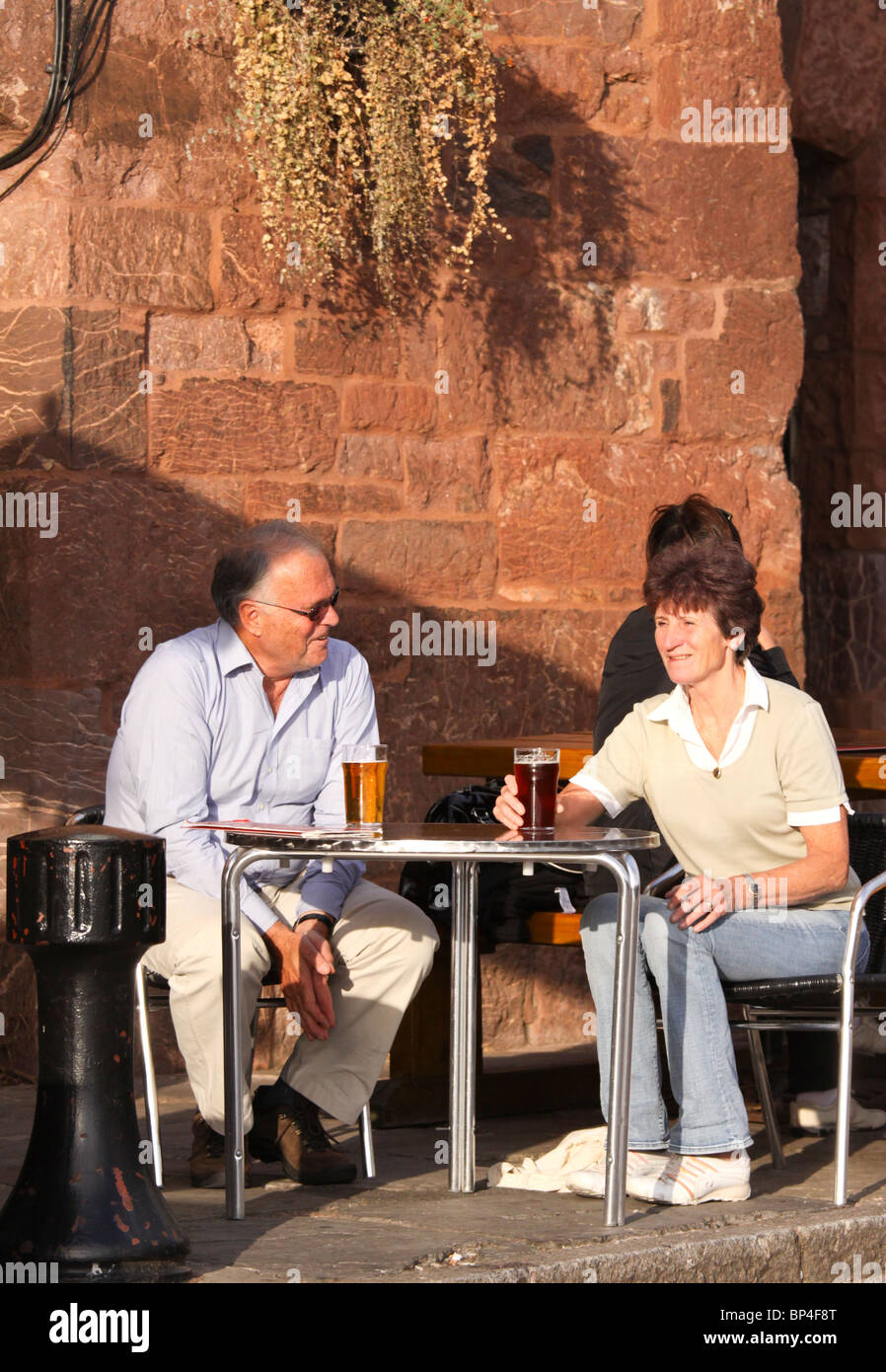 A couple enjoying a drink in the sun down by the river in Exeter Stock ...