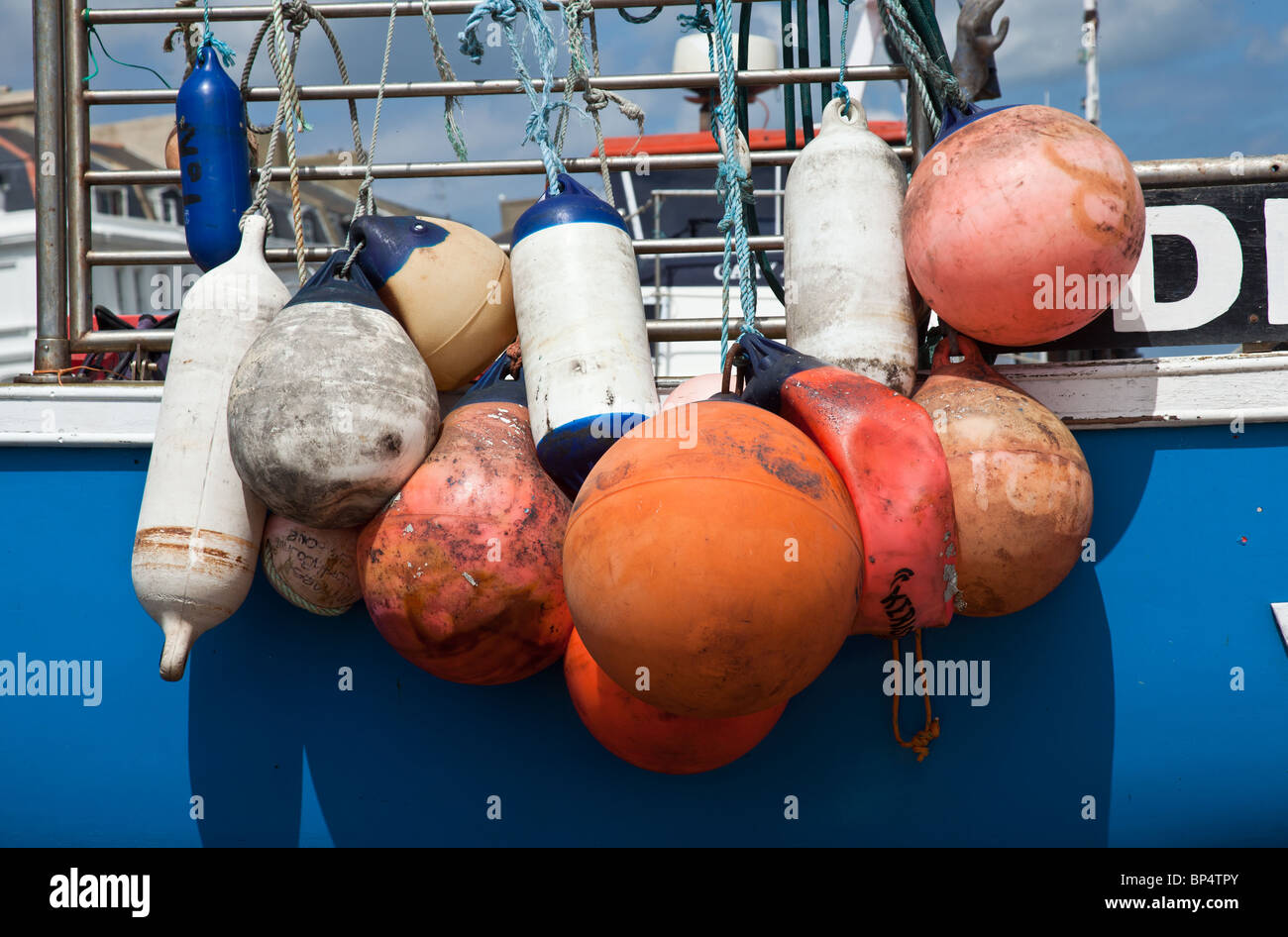 Group of colored plastic floats on side of blue boat used as bumpers ...