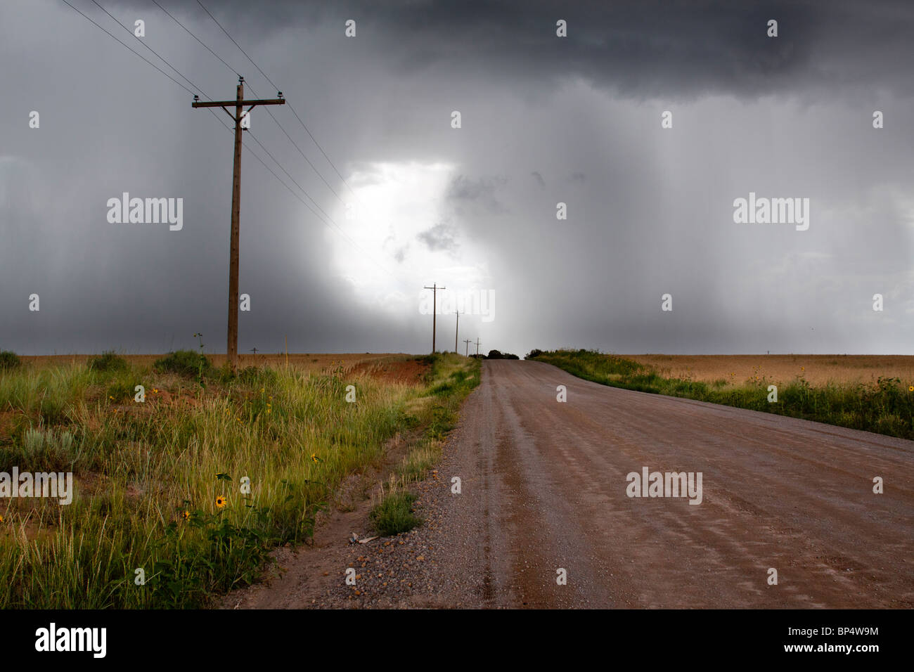 Rural thunderstorm scene - dirt road leads to bright light in sky ...