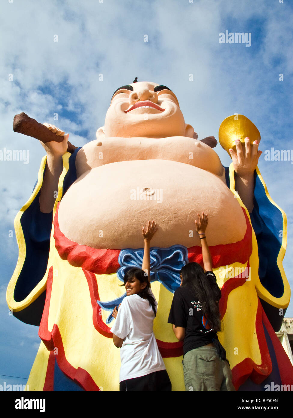Two young women touch the belly of Kuan Yin statue for luck at Chinese ...