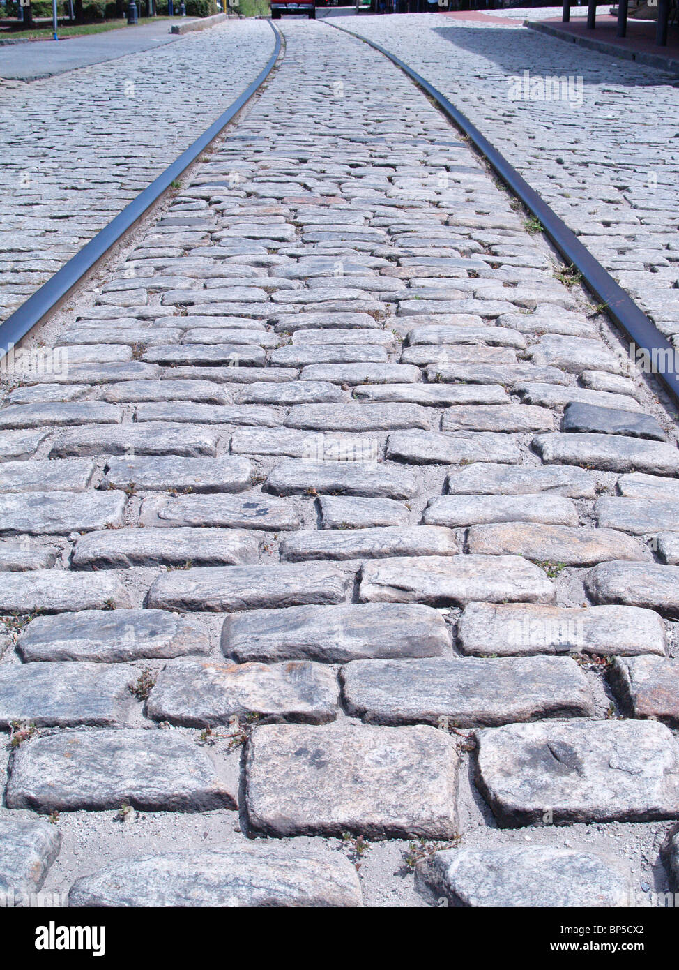 Train tracks embedded in down the middle of an old cobblestone road ...