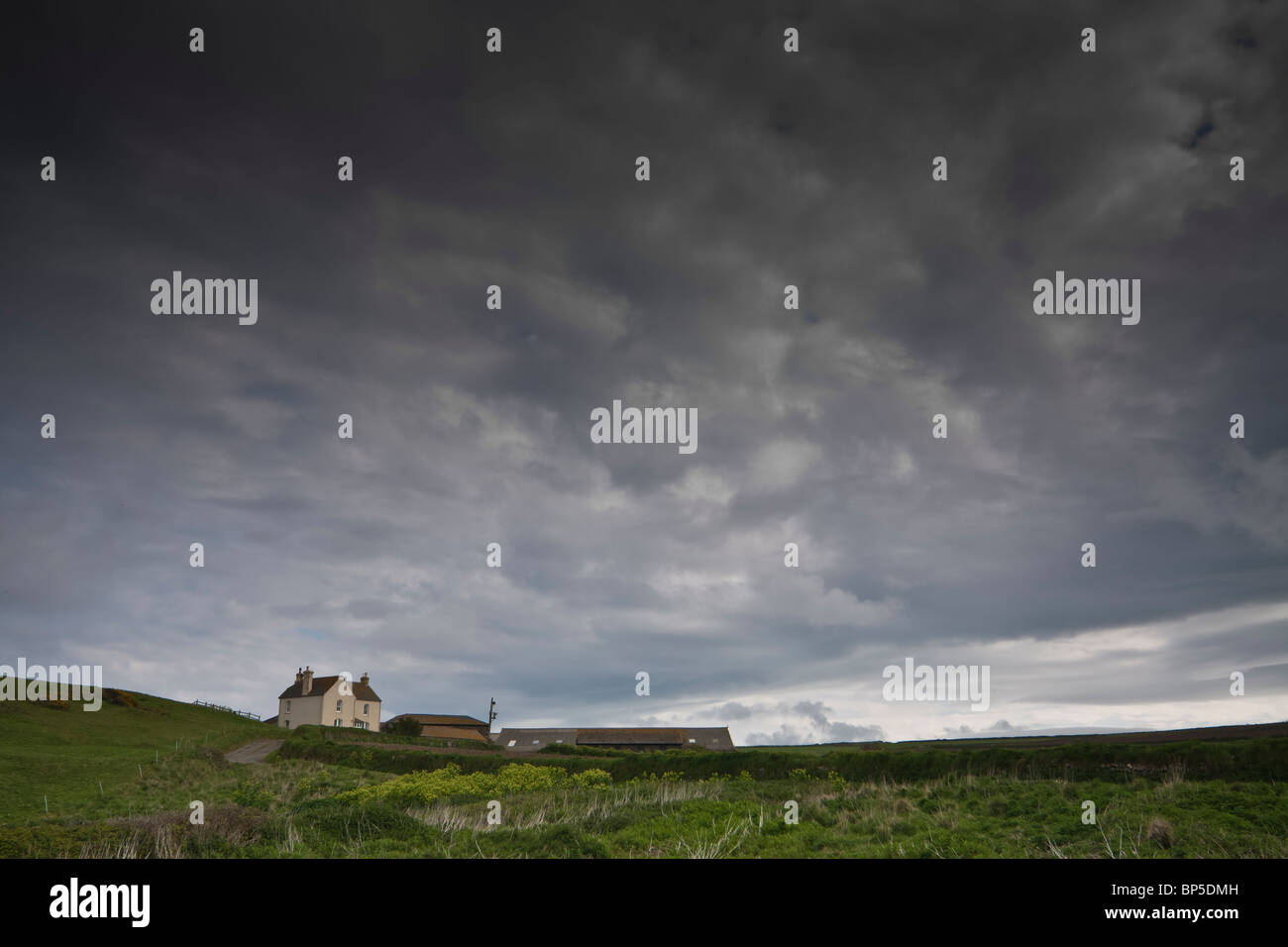 Farm on a hill with dramatic overcast sky Stock Photo - Alamy