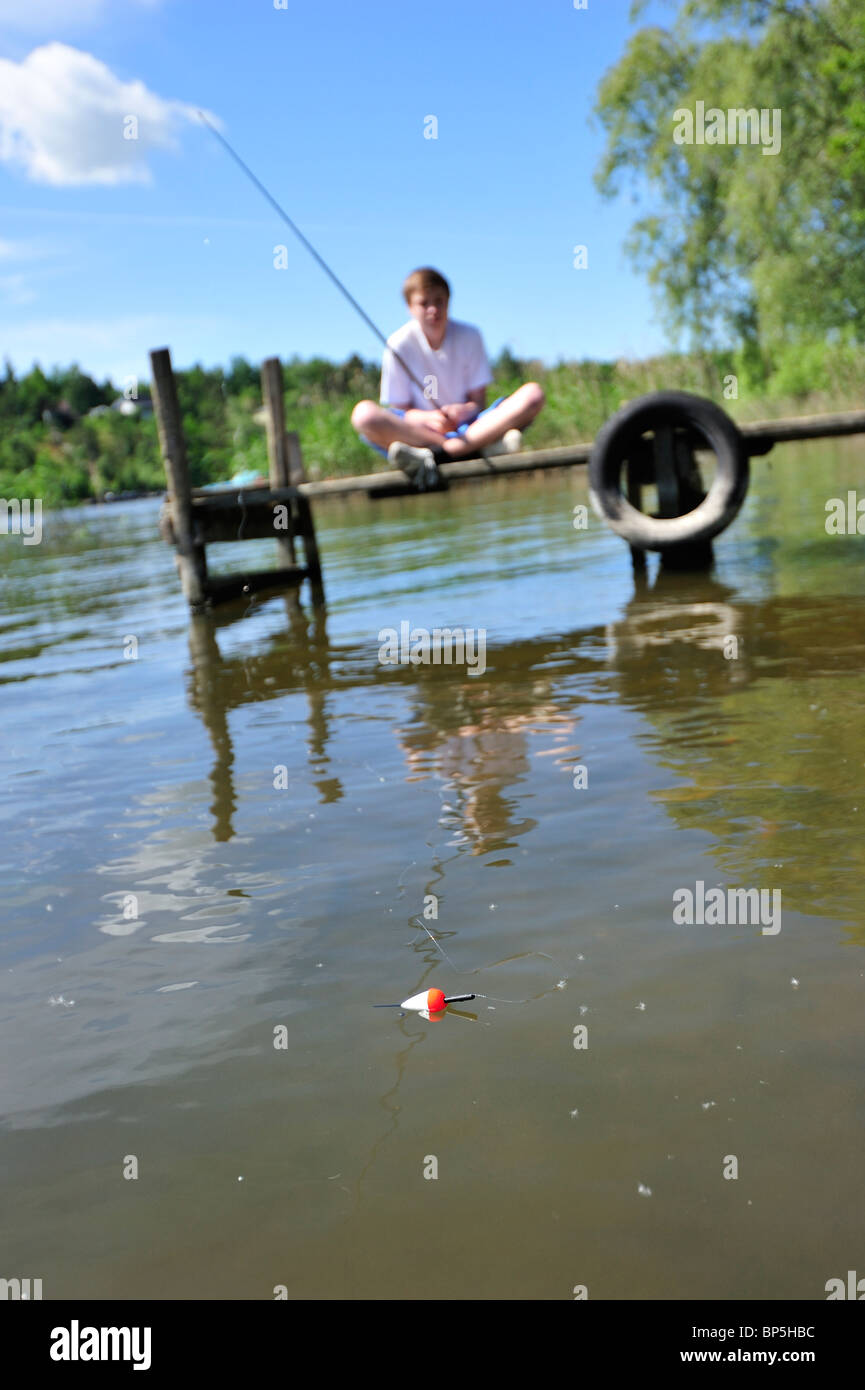 Boy sitting on a bridge fishing perch a warm summer day Stock Photo - Alamy