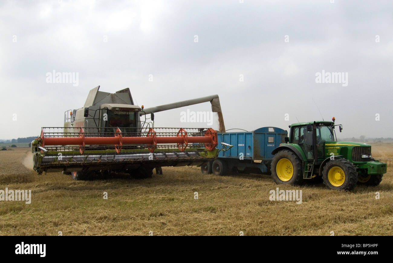 Claas combine harvester unloading grain into trailer pulled by John ...