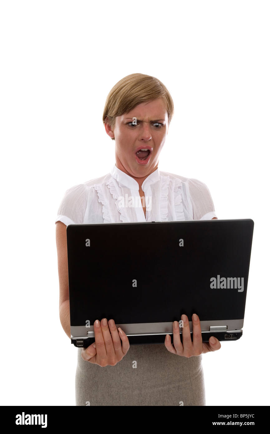 Woman holding laptop and looking at screen in shock horror Stock Photo ...