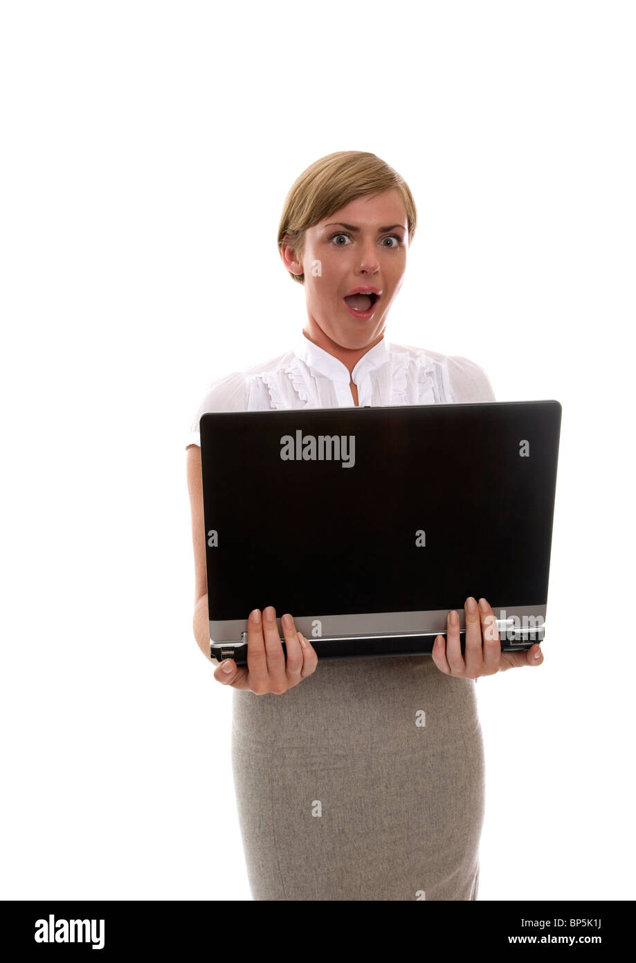 Woman holding laptop and looking at screen in shock Stock Photo - Alamy