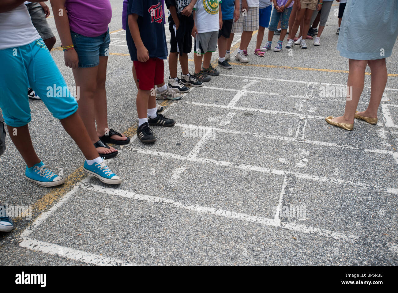 Elementary school age children and their teacher line up on a hopscotch ...