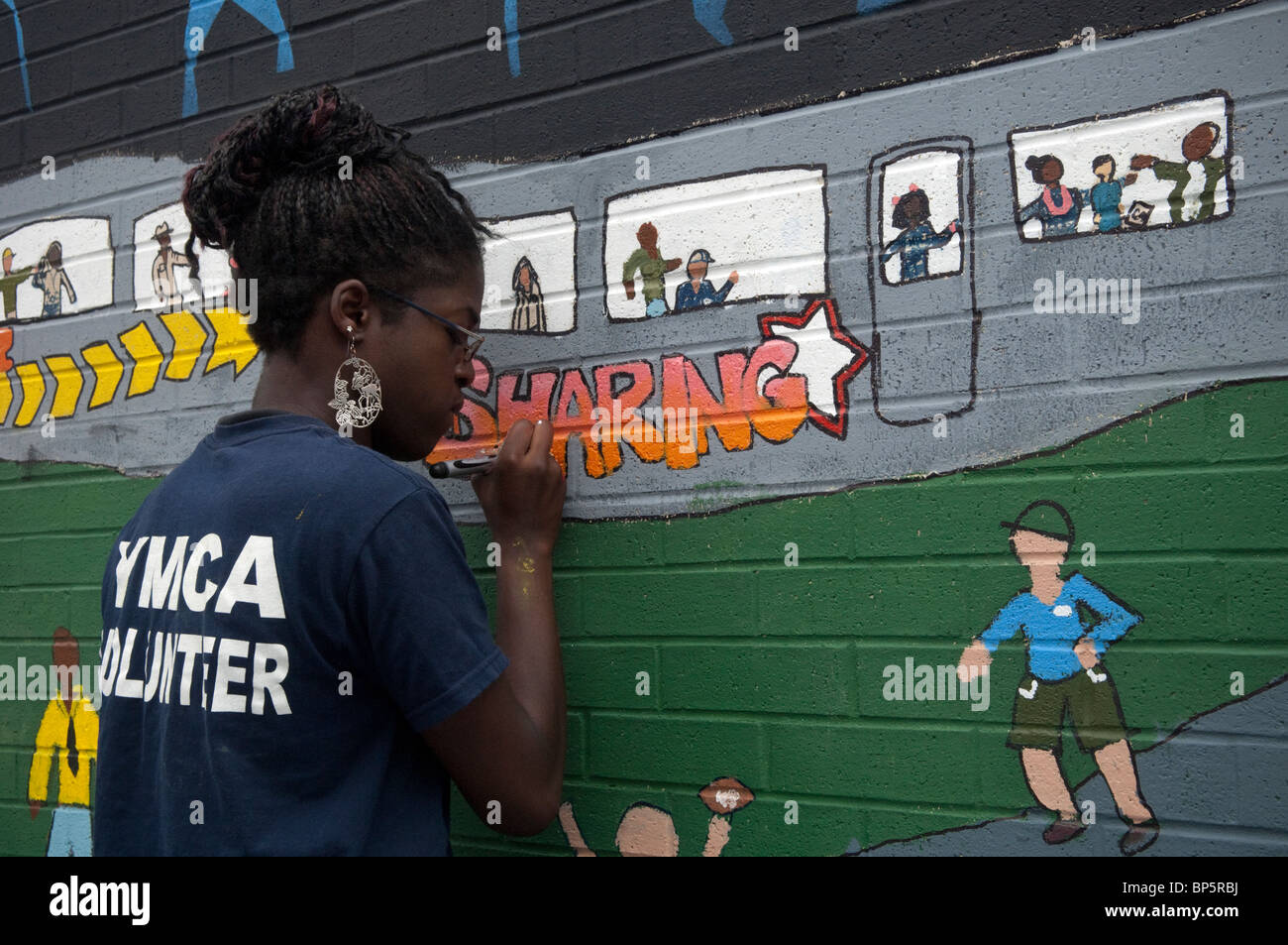 Volunteers and students paint a mural against bullying at a middle ...