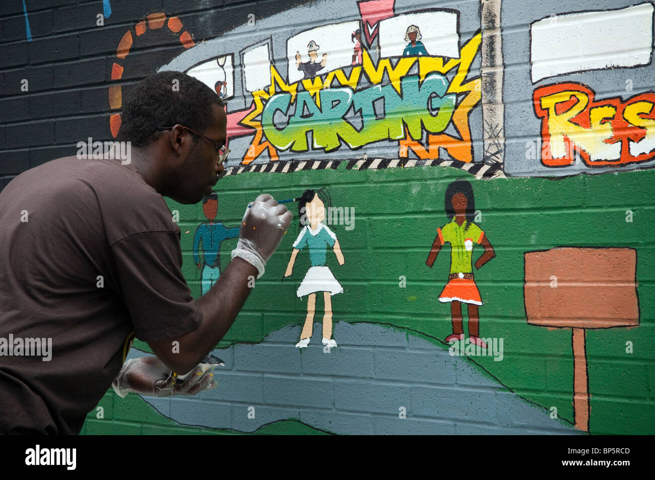 Volunteers and students paint a mural against bullying at a middle ...