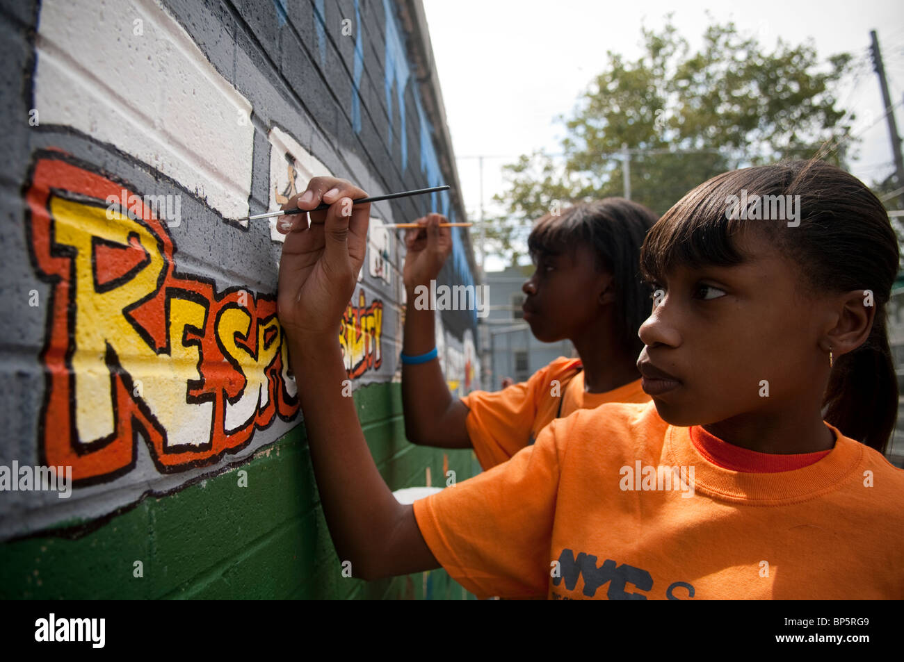 Volunteers and students paint a mural against bullying at a middle ...