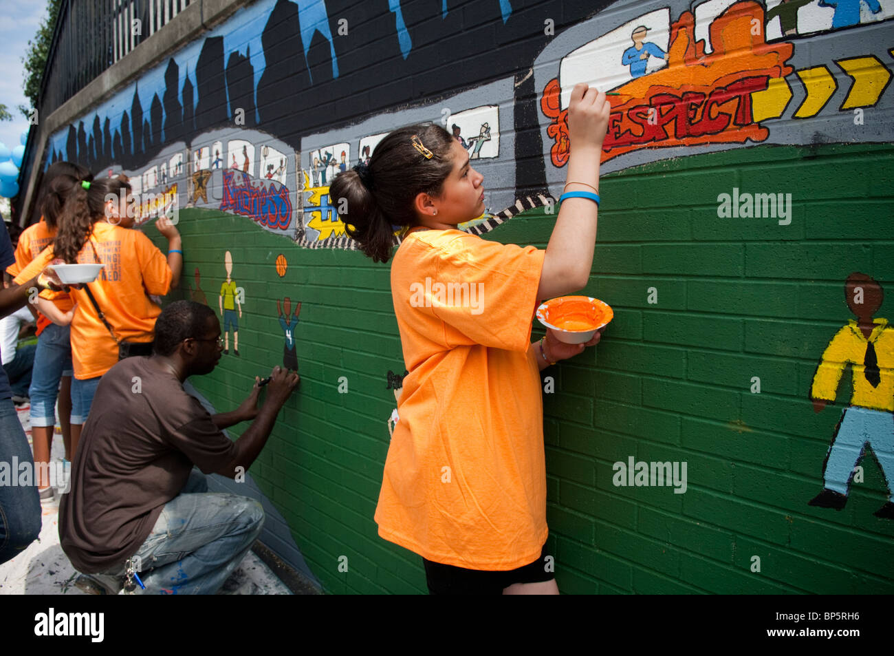 Volunteers and students paint a mural against bullying at a middle ...