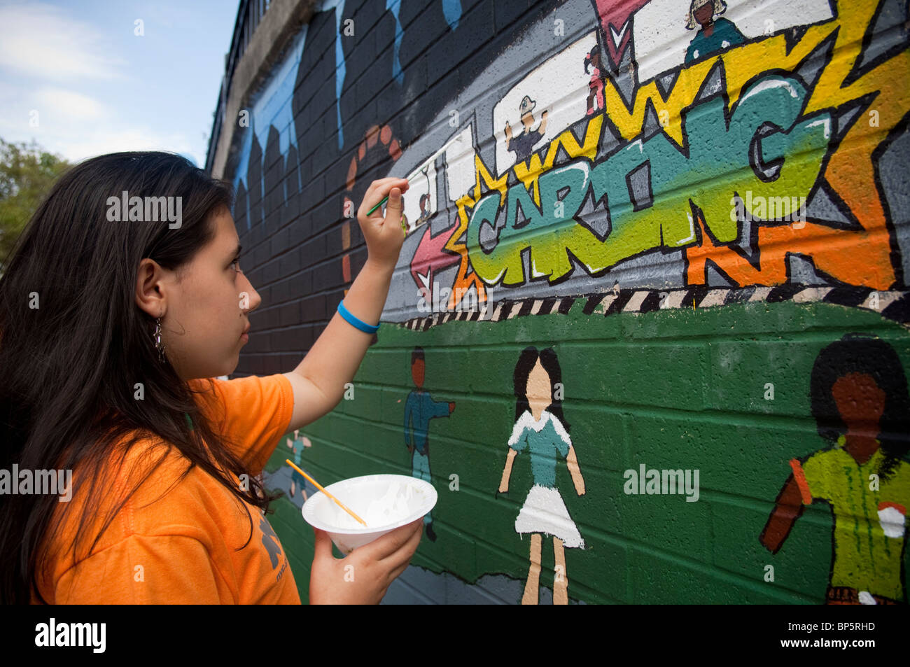 Volunteers and students paint a mural against bullying at a middle ...