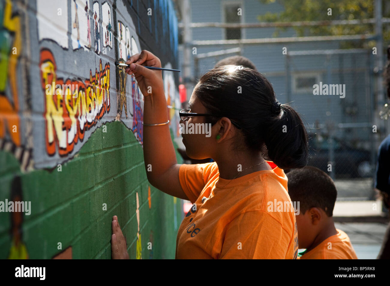 Volunteers and students paint a mural against bullying at a middle ...