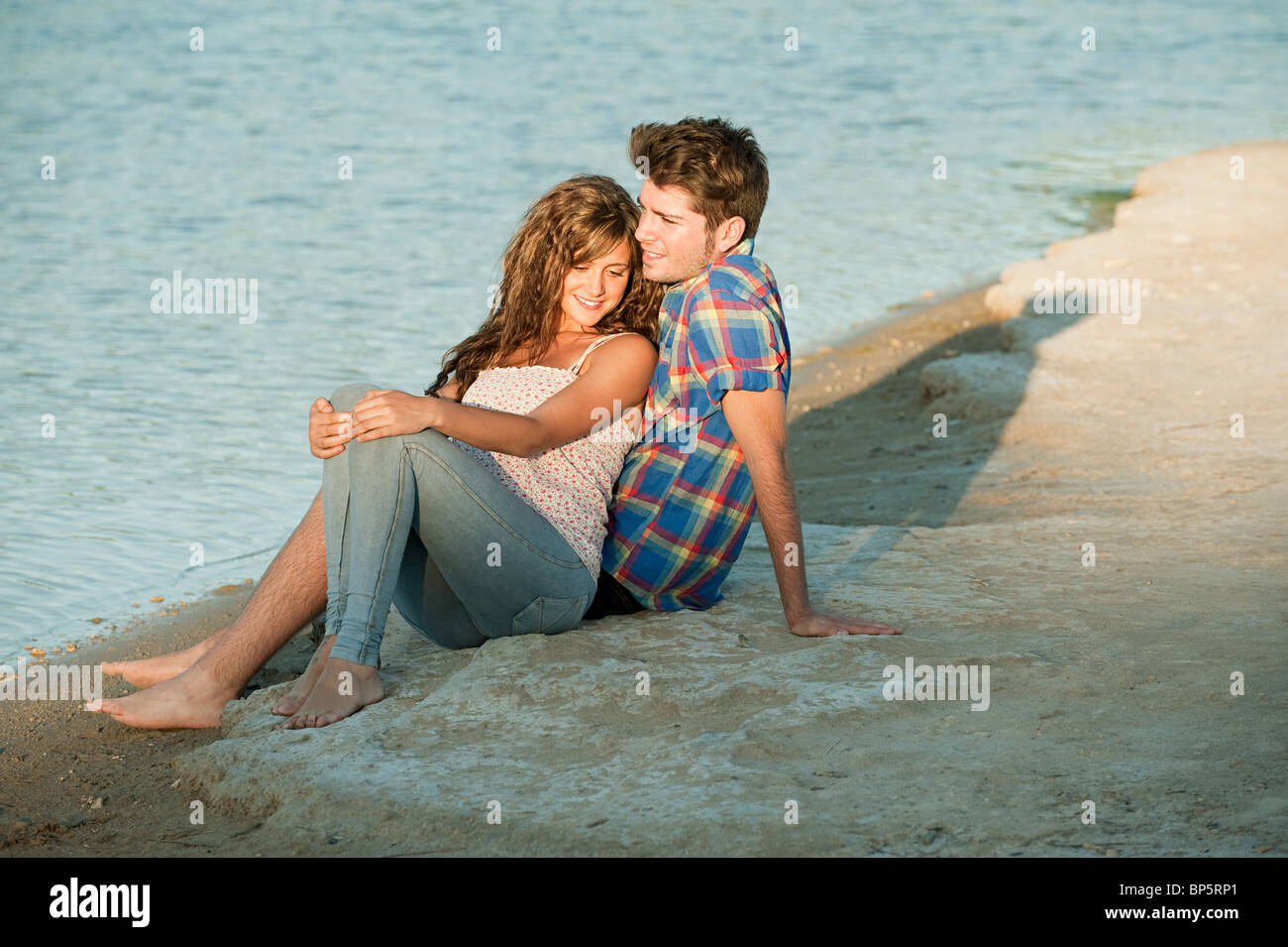 Young couple sitting near lake Stock Photo - Alamy